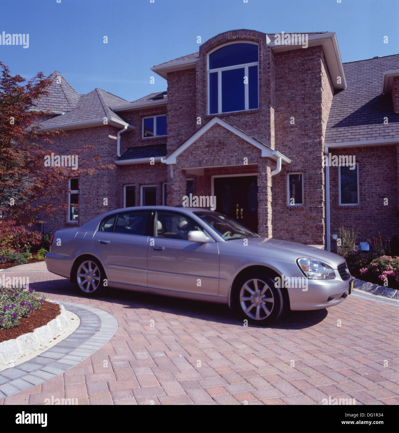 Silver car on paved drive in front of new-build traditional brick house ...