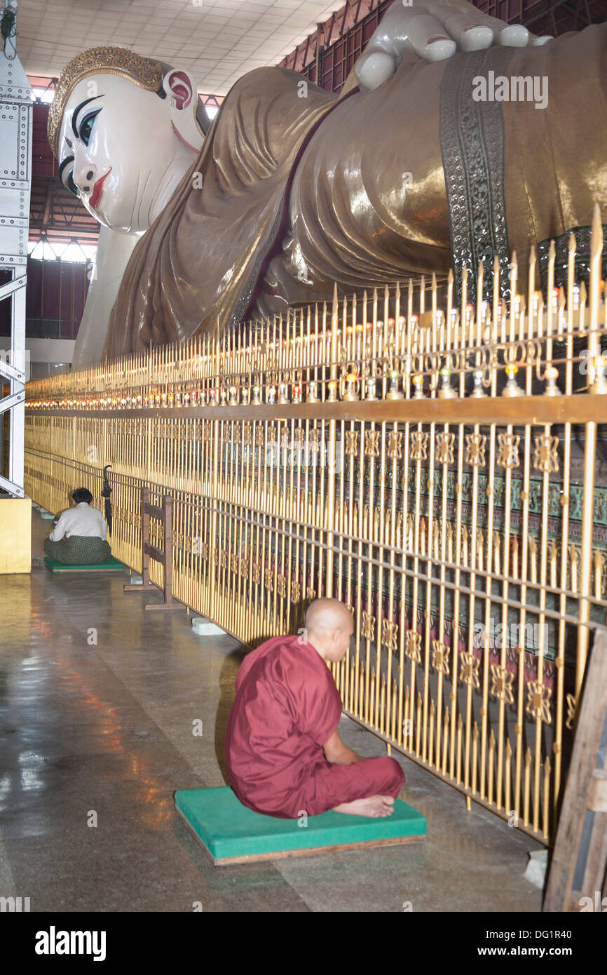Buddhist monk praying beside reclining Buddha, Chaukhtatgyi Pagoda ...