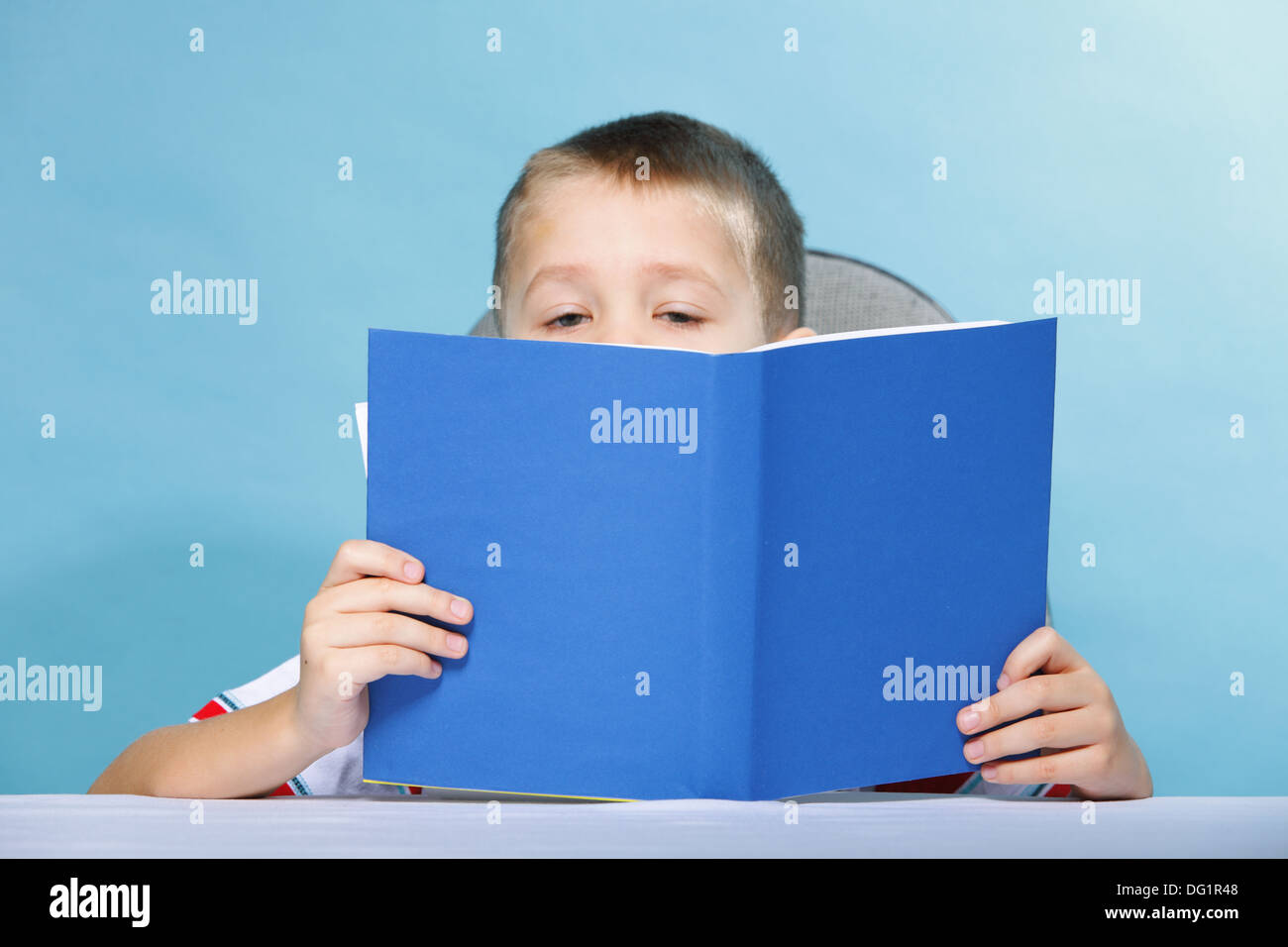 Young boy reading a book, child kid on blue background holding an open ...