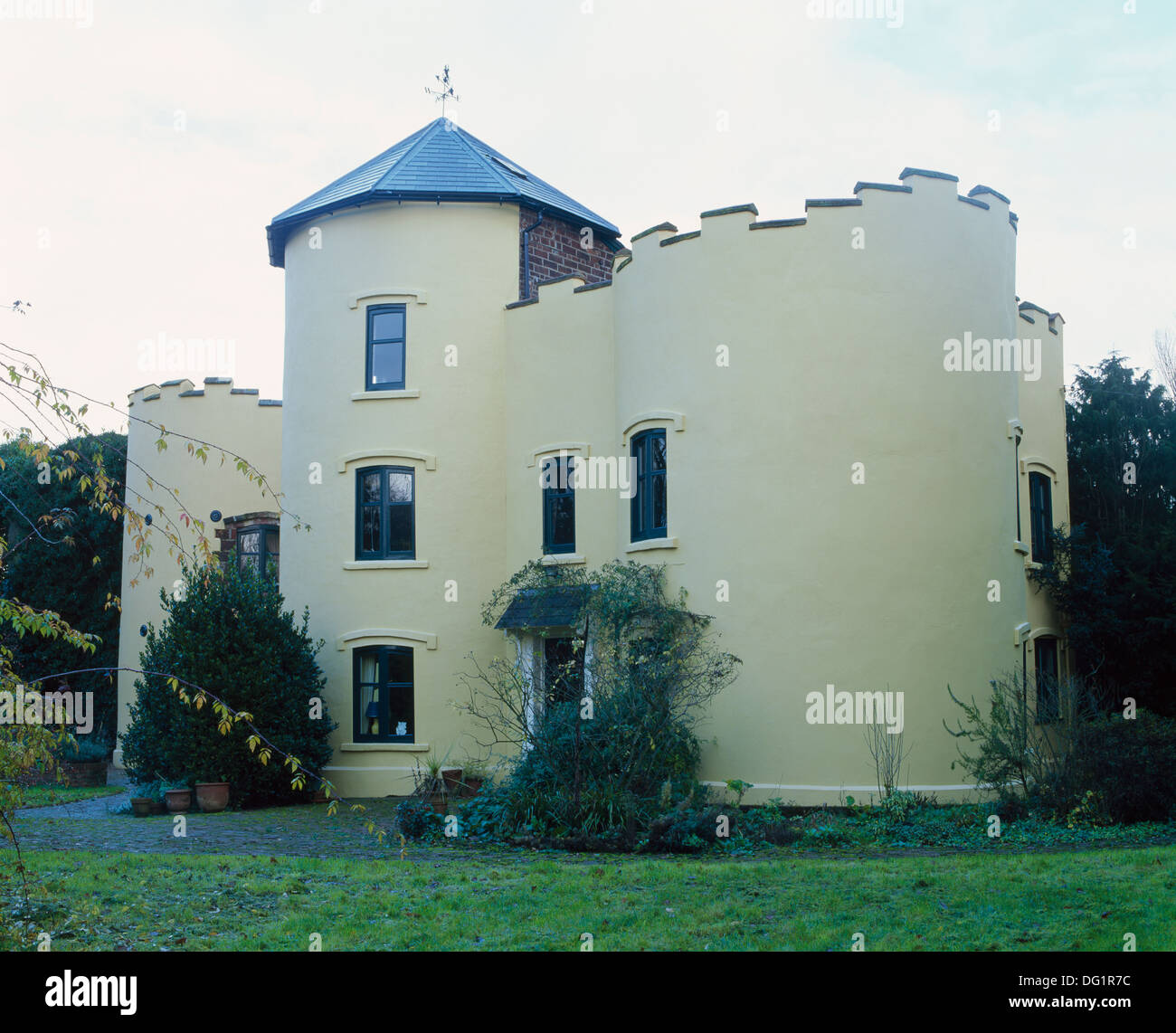 Newly painted cream castellated country house with turret in the centre ...