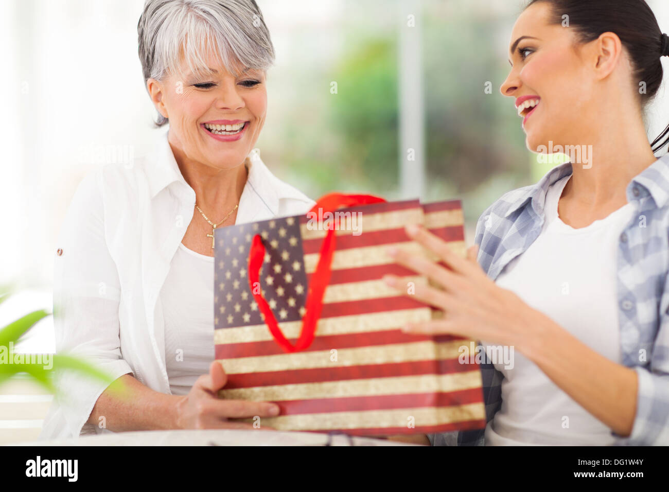 beautiful young woman giving her senior mother a gift Stock Photo - Alamy