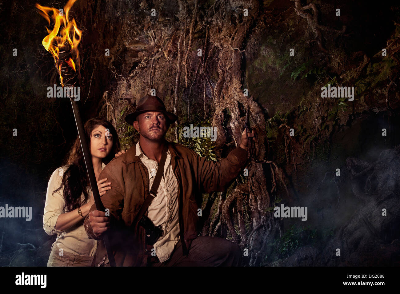 Indiana Jones styled adventure hunter in cave with woman carrying torch ...