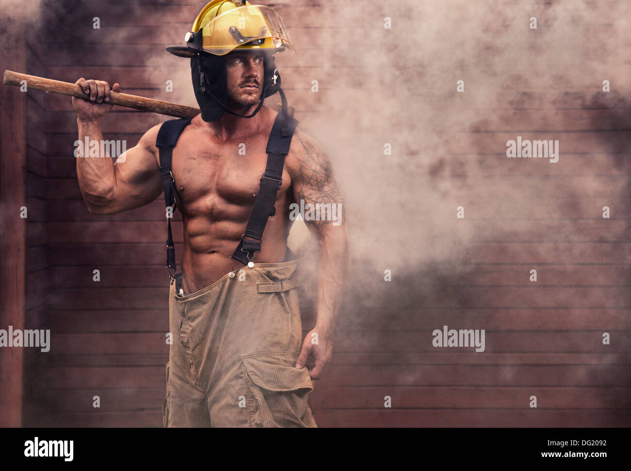 Muscular fireman in front of smoky building Stock Photo - Alamy