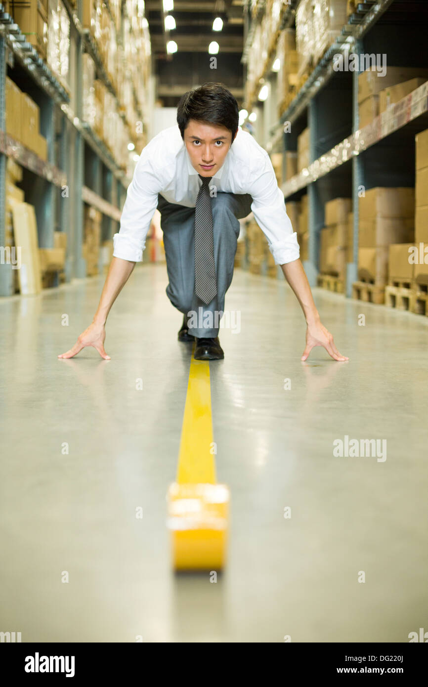 Confident businessman ready to run in warehouse Stock Photo - Alamy