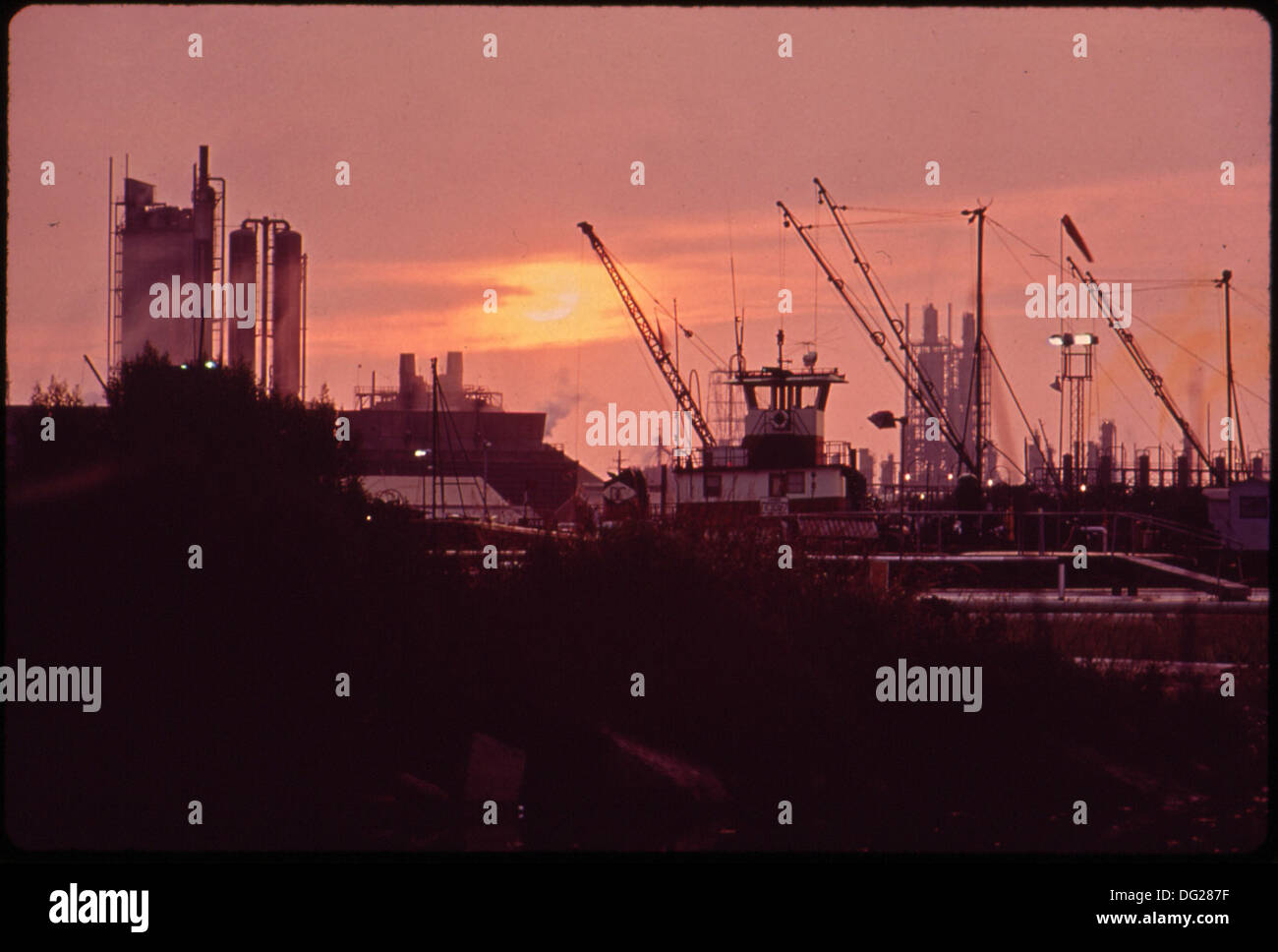 The photograph shows a sunset over the Olin-Mathieson plant, an ...