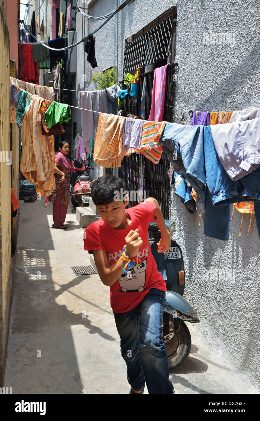 Boy running on street in poor neighborhood of Delhi, India Stock Photo ...