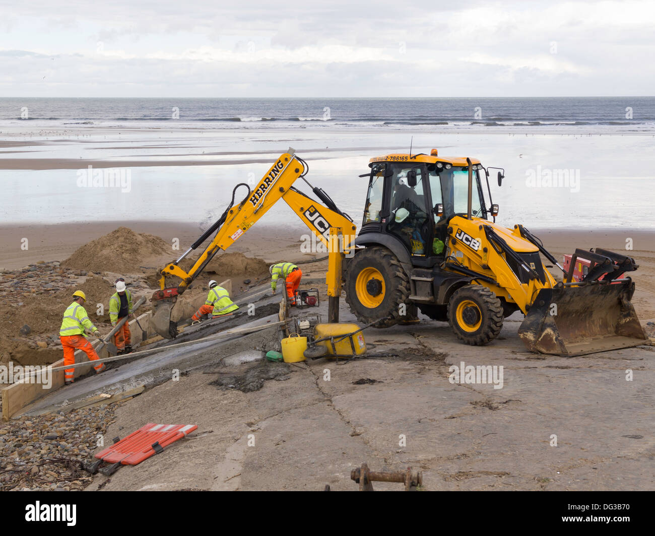 Team of workmen repairing a damaged concrete slipway at Saltburn by the ...