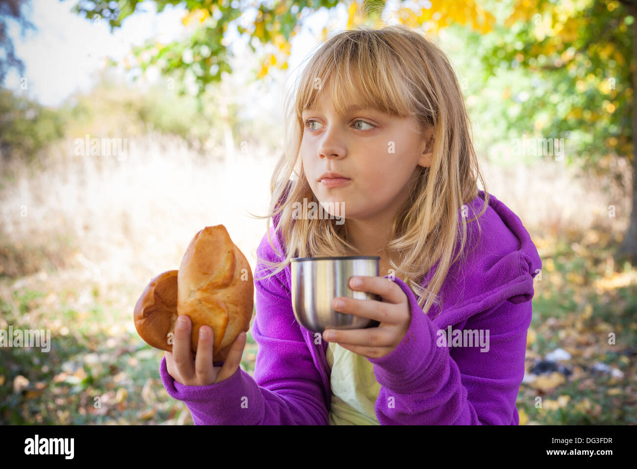 Little blond girl in autumn park eats small pies with tea Stock Photo ...