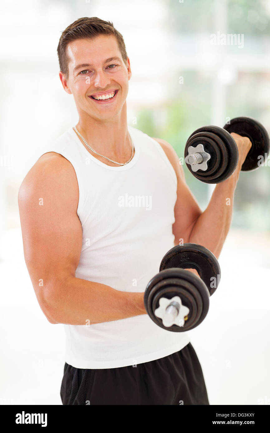 Handsome muscular young man exercises dumbbells hi-res stock ...