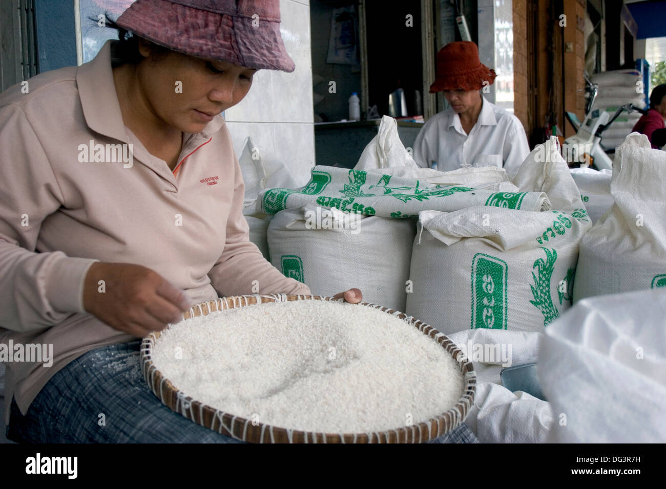 A woman is working with milled rice in a rice store in Phnom Penh ...