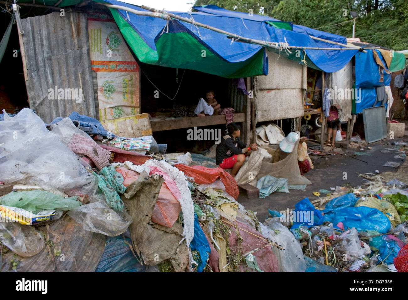 Large bags of garbage are piled near homes of people living in poverty ...
