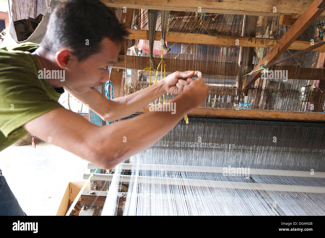 Silk weaver working with a broken thread on a traditional wooden loom ...