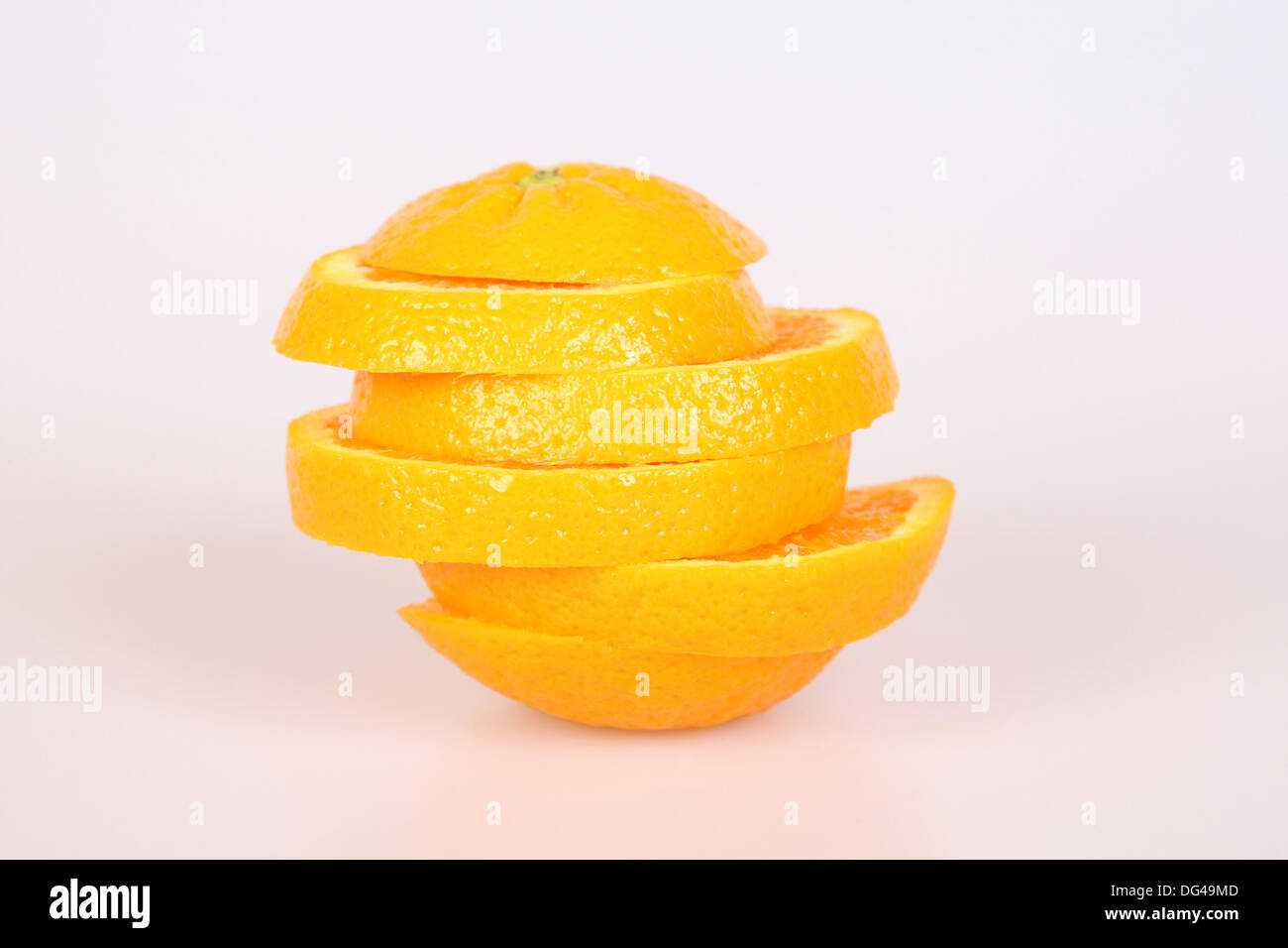 An orange fruit cut horizontally into 6 slices and reassembled against ...