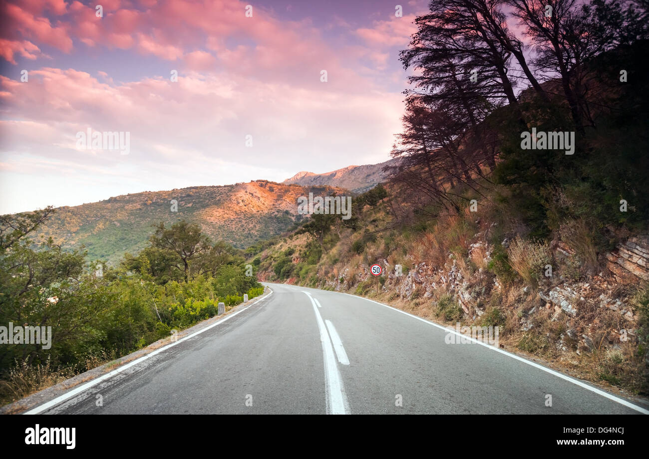 Mountain highway in soft early morning sunlight under colorful cloudy ...