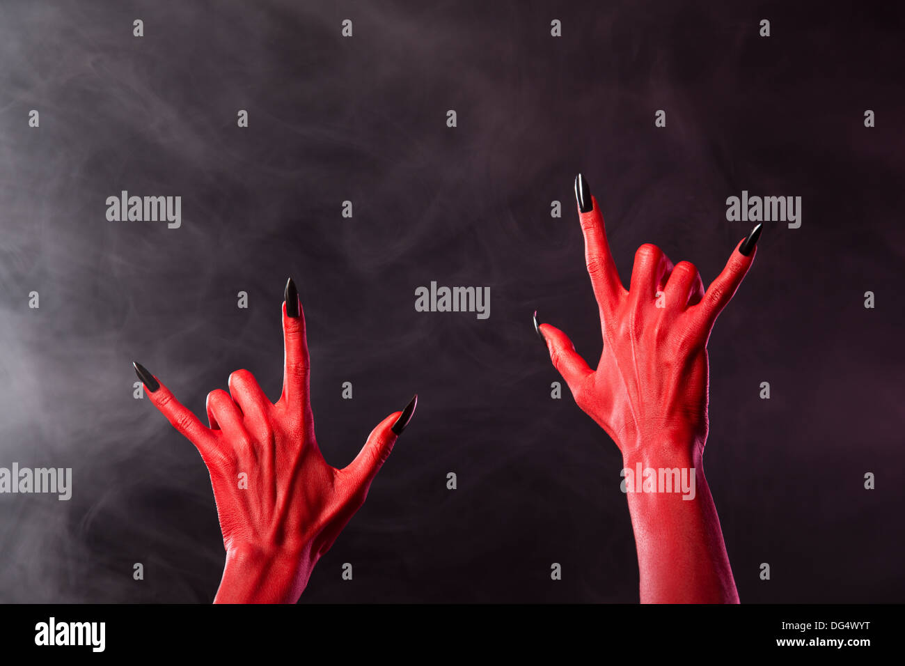 Red devil hands showing heavy metal gesture, studio shot on smoky ...
