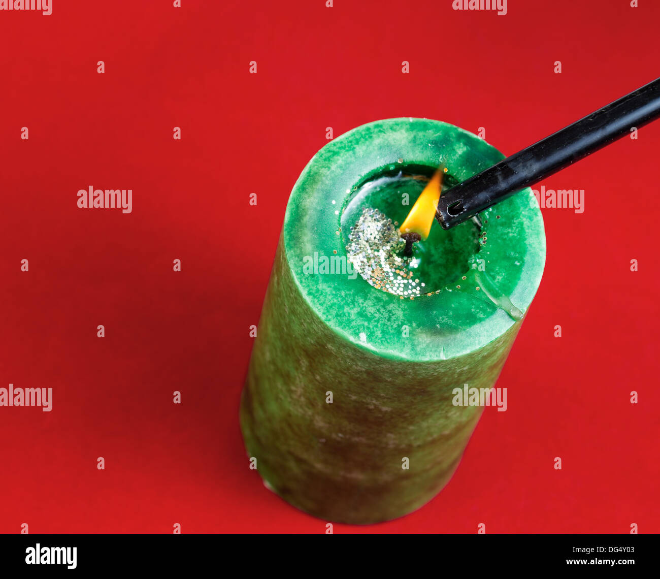Photo of green holiday candle being light with fire starter on red ...