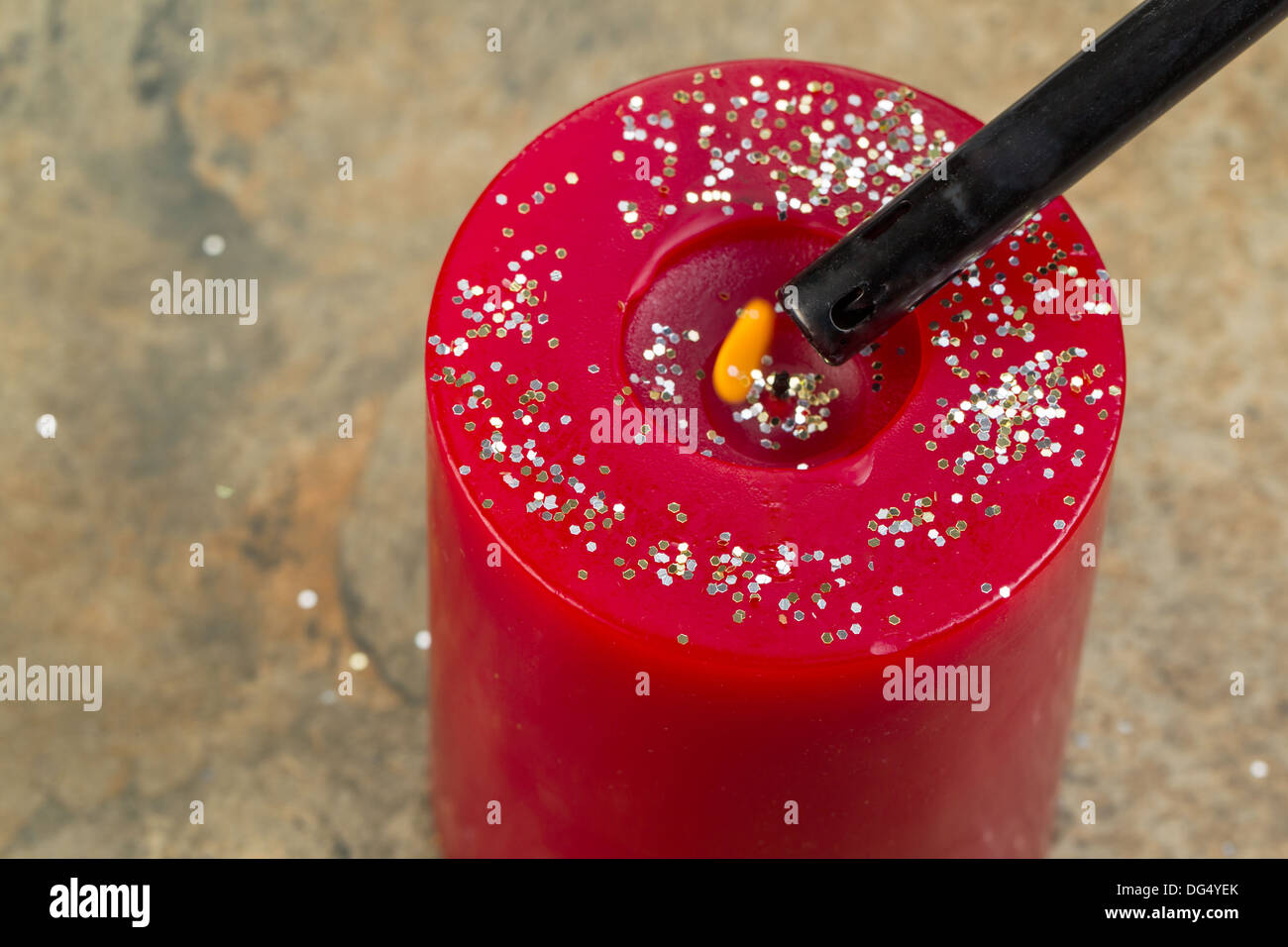 Horizontal photo of red holiday candle being light with fire starter on ...