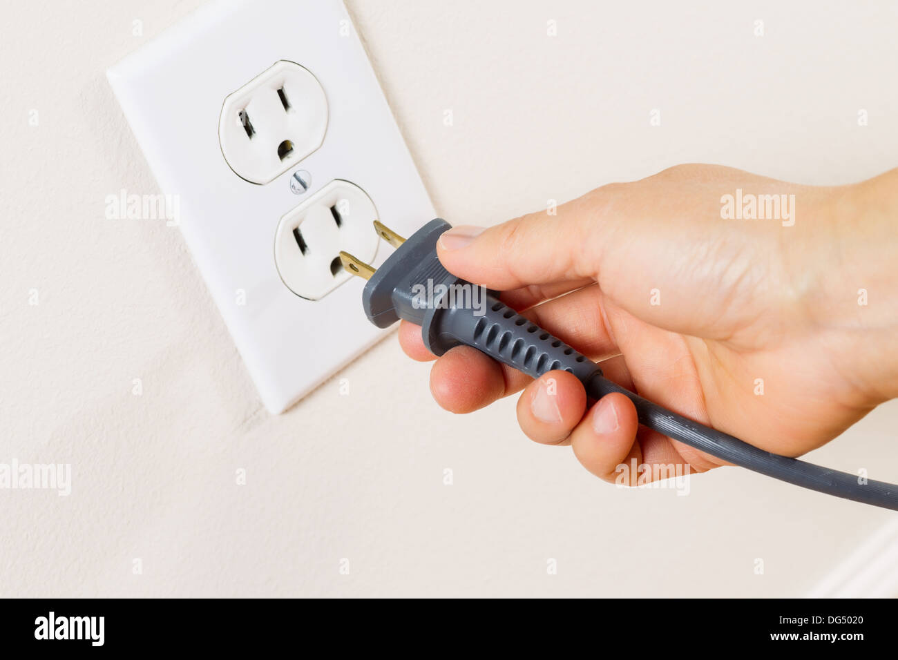 Horizontal photo of female hand inserting power cord receptacle into ...