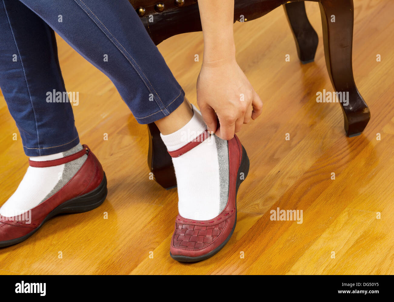 Horizontal photo of woman snapping strap on causal shoes while sitting ...