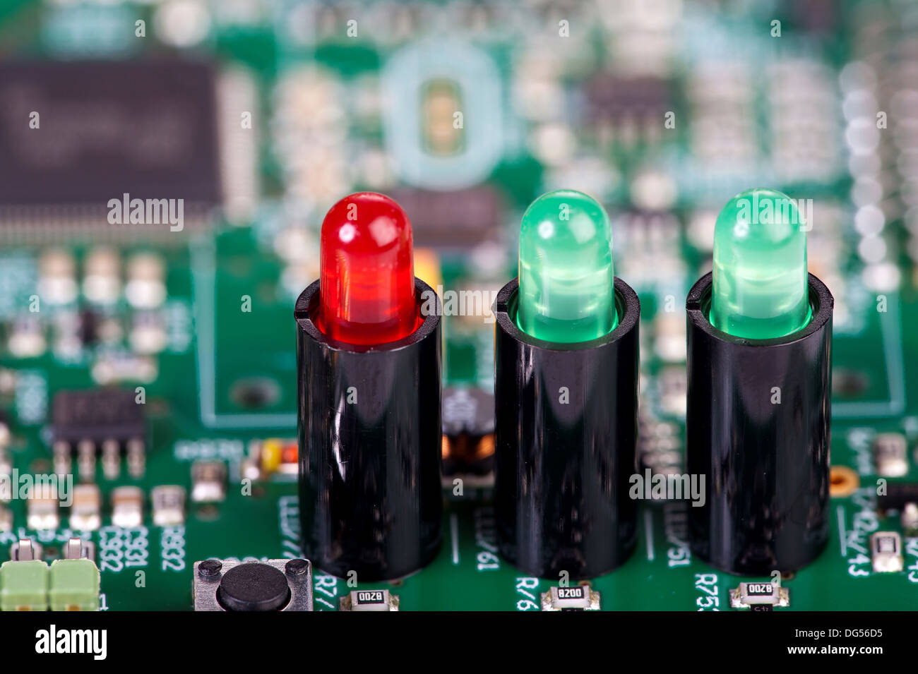 Two green and one red LED in sockets on a circuit board as Close-up ...