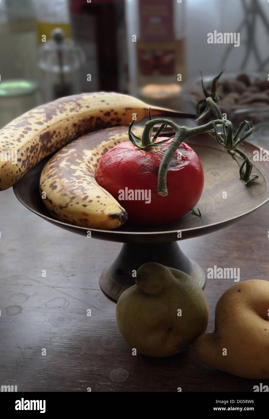 kitchen table: we see an overripe tomato and bananas on a pedestal ...