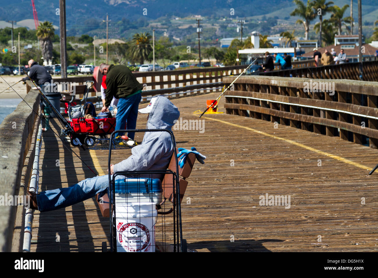 People fishing, relaxing, and strolling on a wooden pier in Goleta ...