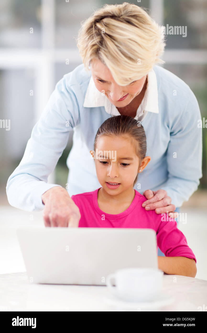 senior grandmother teaching grandchild how to use laptop computer at ...
