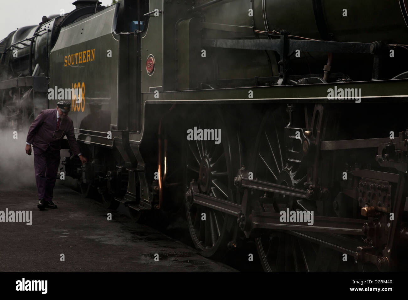 Steam engine driver checks the workings of his Southern 1638 locomotive ...