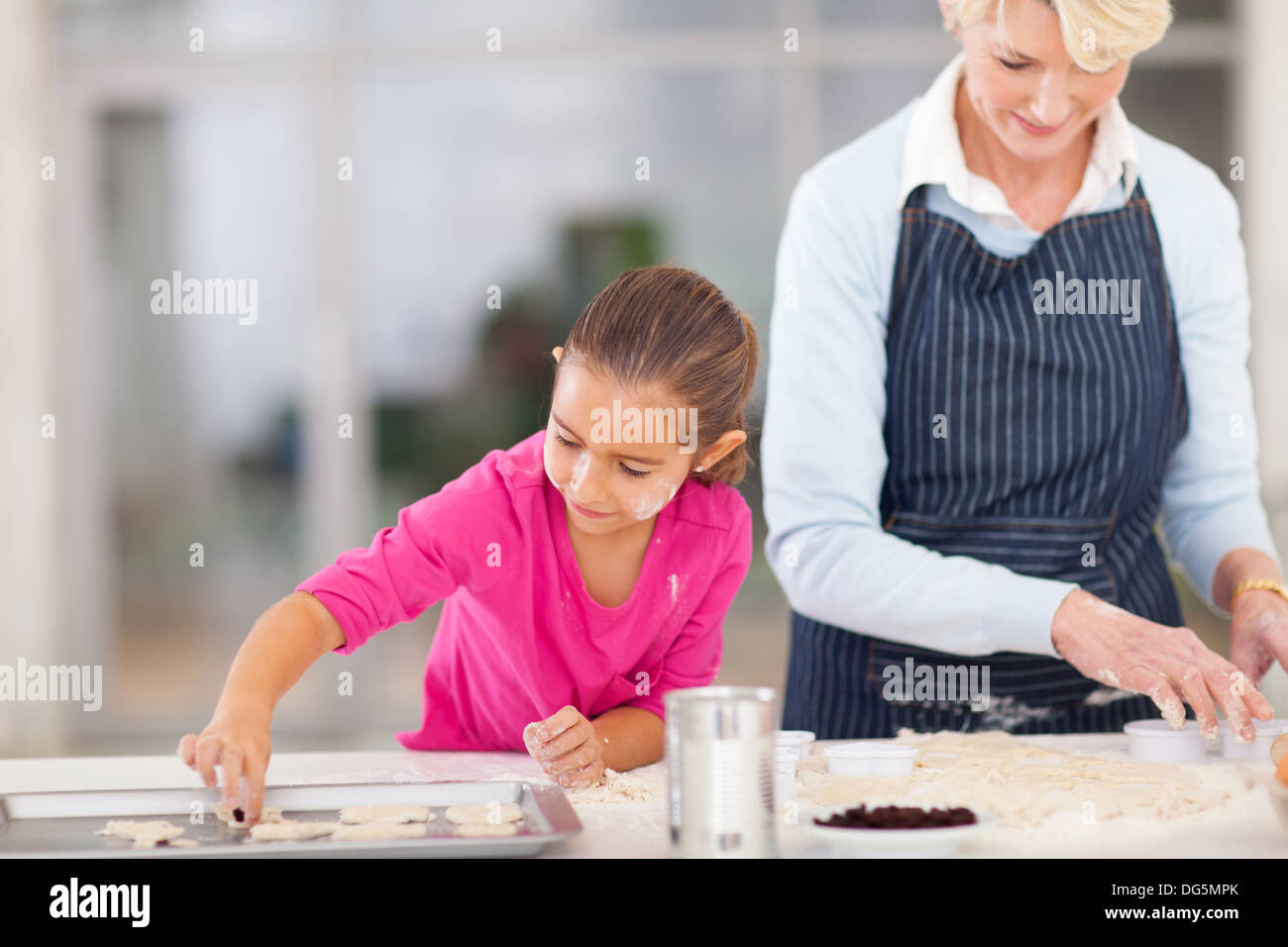 senior grandmother baking cookies with granddaughter in kitchen Stock ...