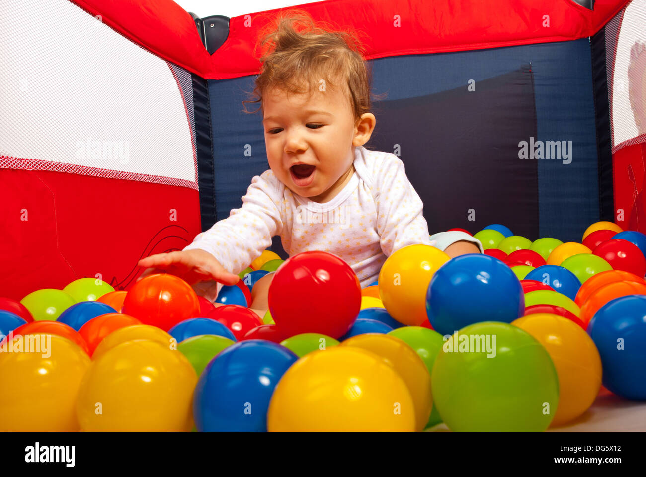 Happy baby playing with balls in playpen Stock Photo - Alamy