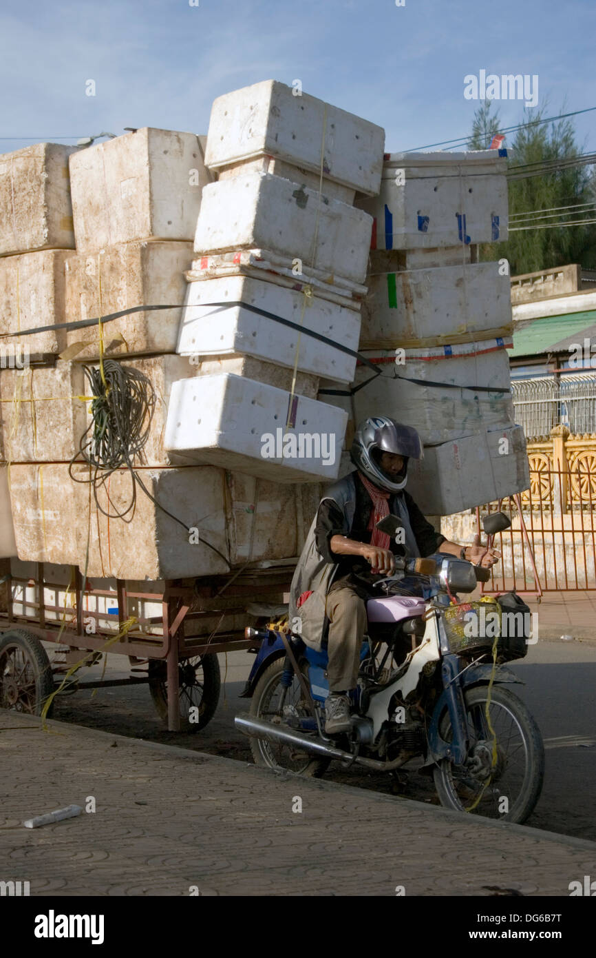 A delivery man riding a motorcycle is stopped on his route with a large ...