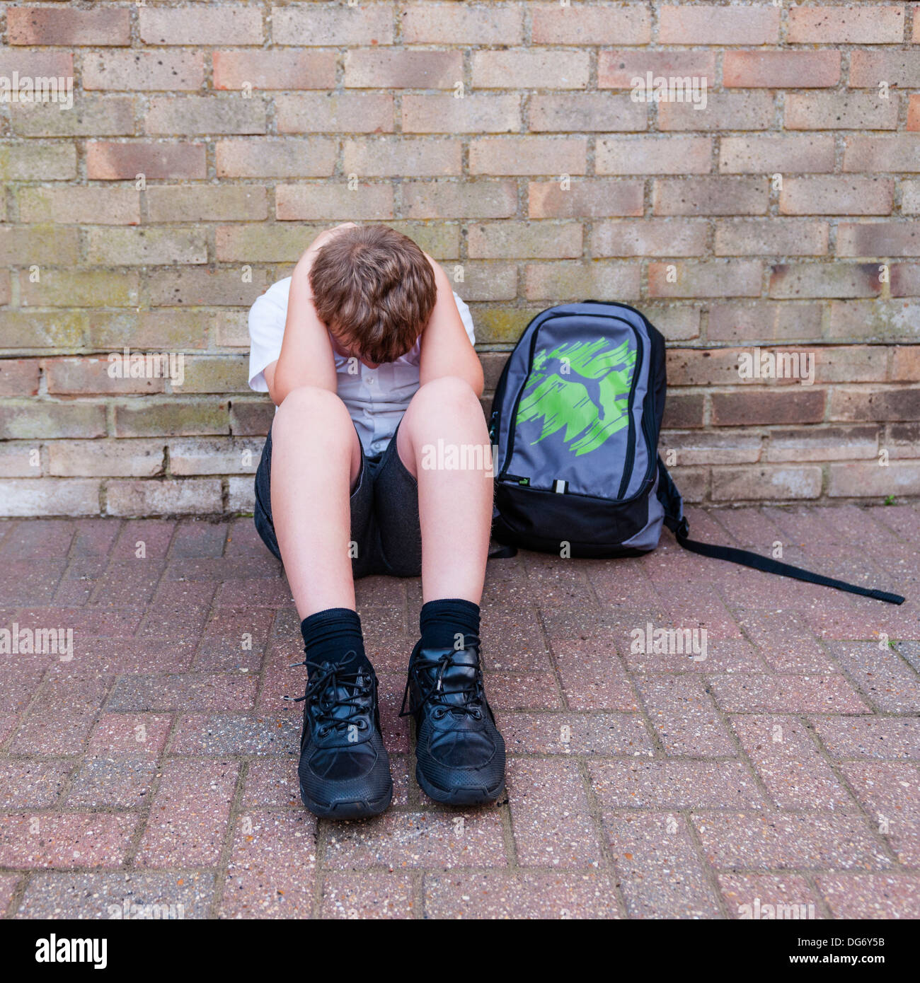 A boy of 10 looking sad and depressed in his school uniform showing the ...