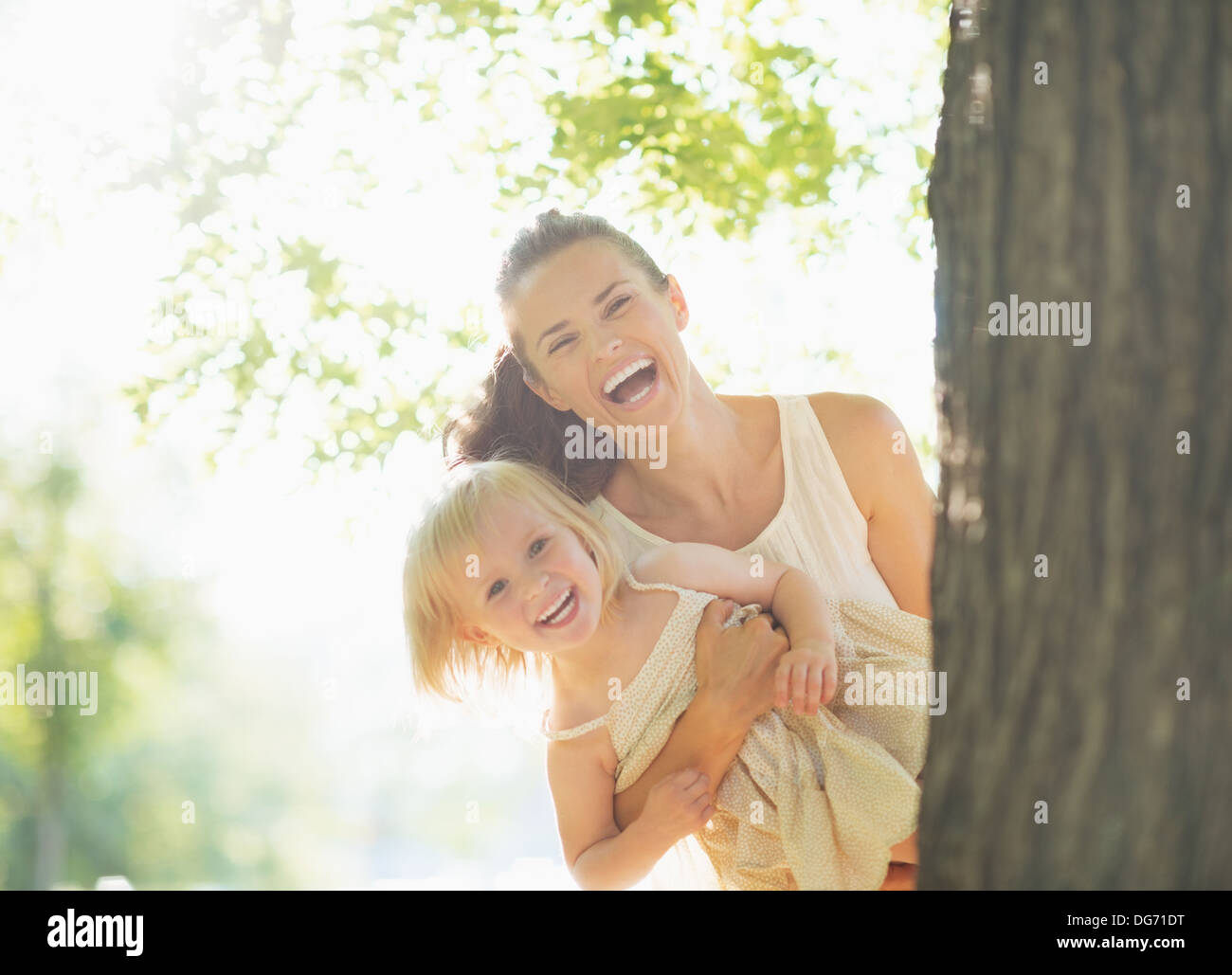 Happy mother and baby looking out from tree Stock Photo - Alamy