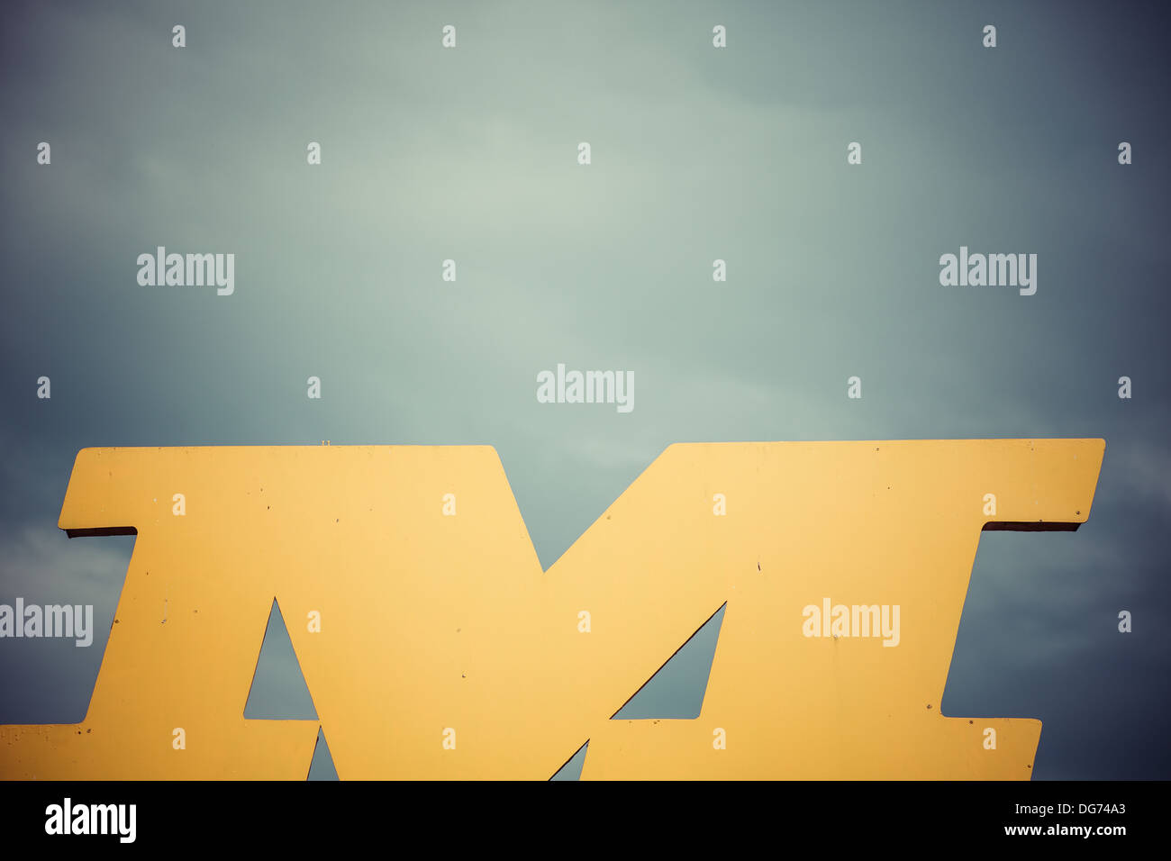 Yellow and designed shape of letter m with heavy sky in the background ...