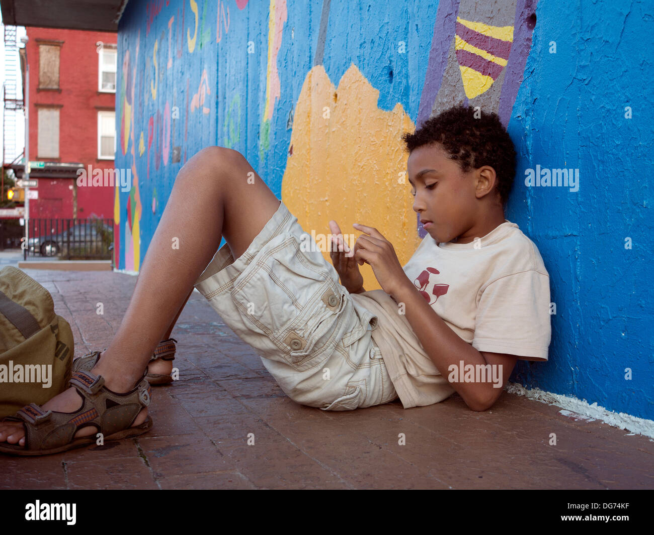 Young boy half laying half sitting on the floor against a cheerily ...