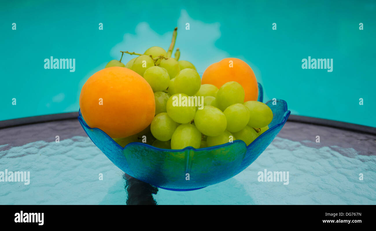 Grape and apricots in glass plate on table by the swimming pool Stock ...