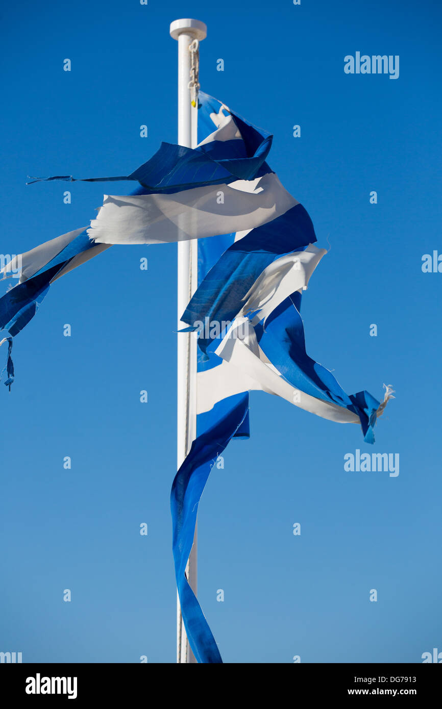 A broken greek flag waving with the wind with a clear blue sky in the ...