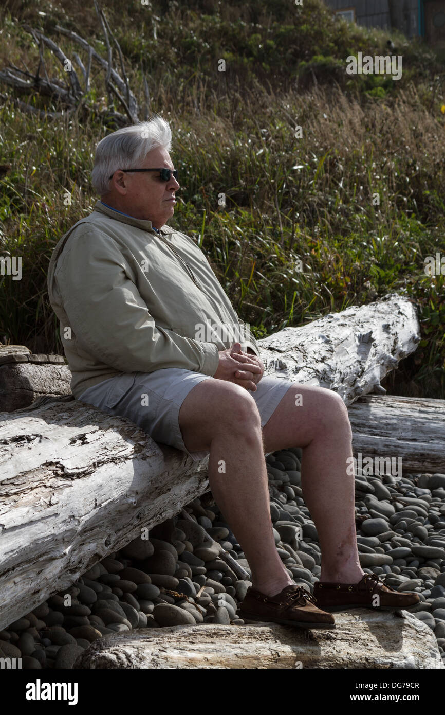 Man sitting on log at the Oregon Coast Stock Photo - Alamy