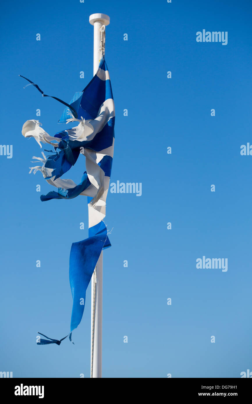 A broken greek flag waving with the wind with a clear blue sky in the ...