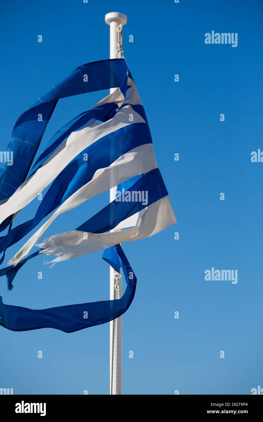 A broken greek flag waving with the wind with a clear blue sky in the ...