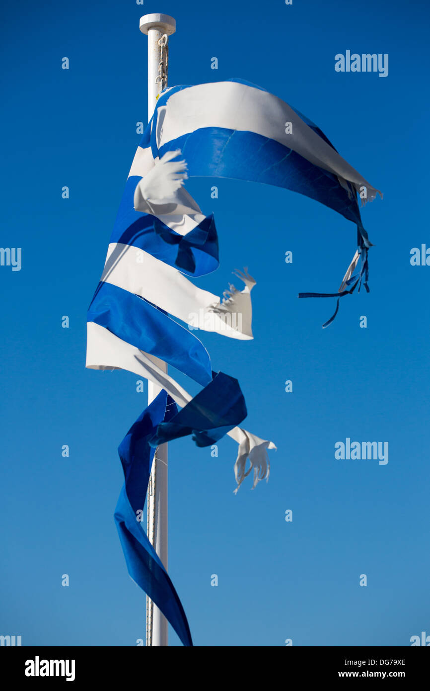 A broken greek flag waving with the wind with a clear blue sky in the ...