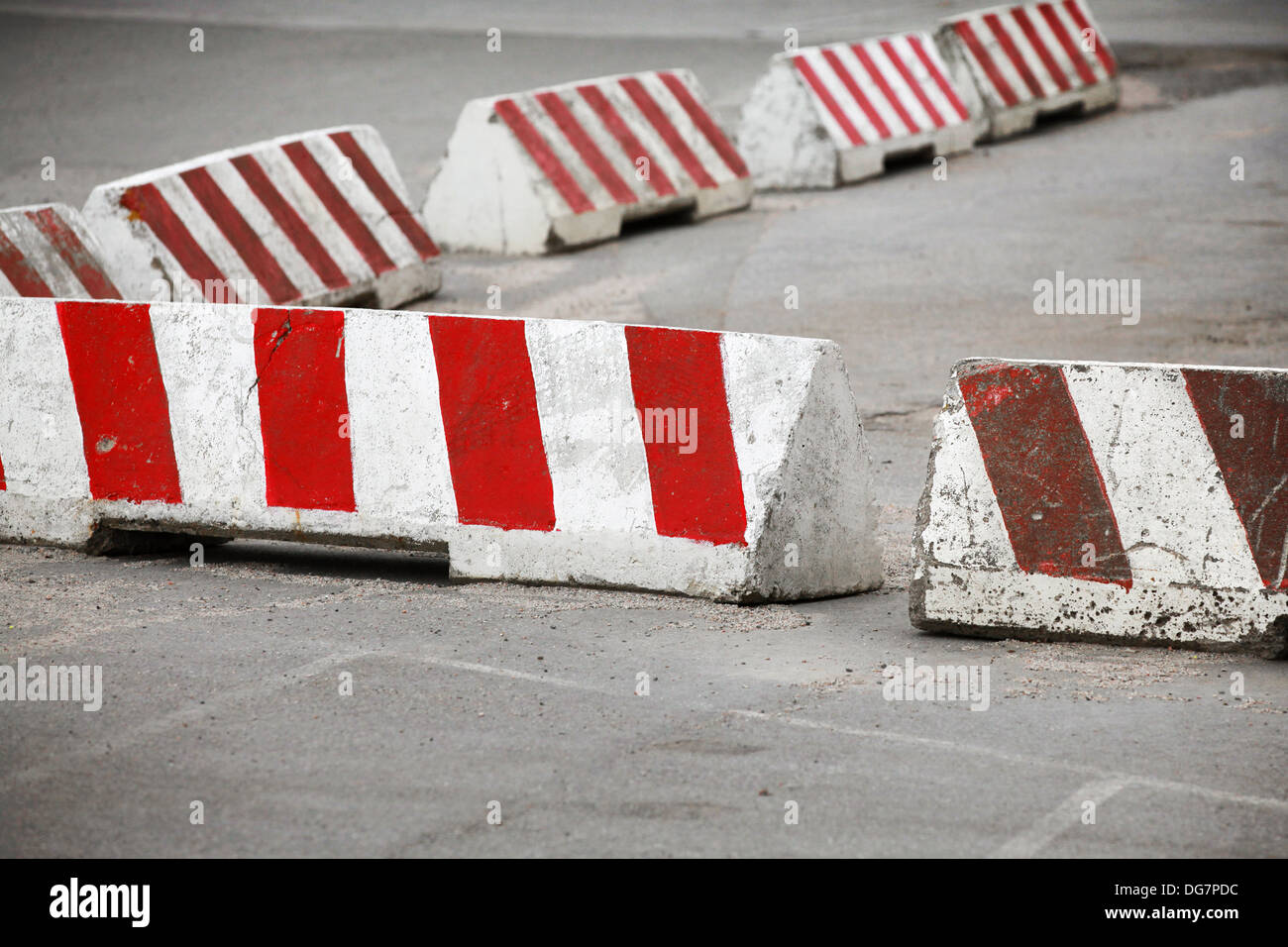 Red and white striped concrete road barriers lying on the asphalt ...