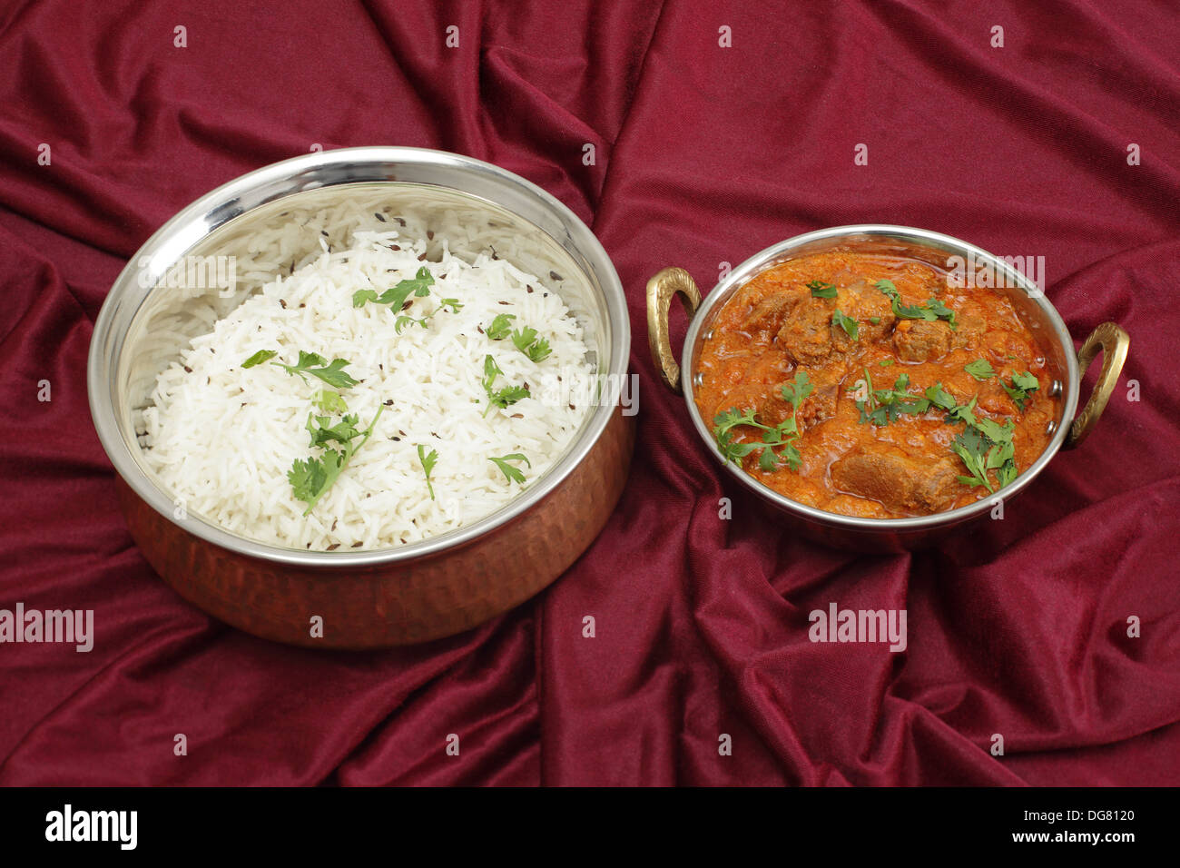 Lamb rogan josh, served with jeera (cumin) rice in beaten copper bowls ...
