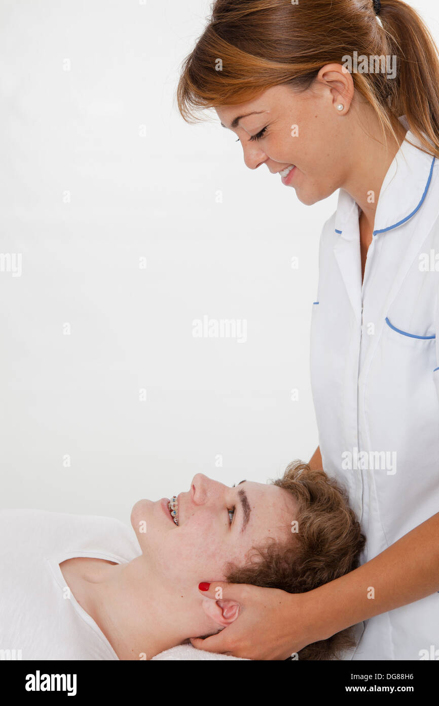 Young female osteopath doctor treating young male with neck pain doing ...