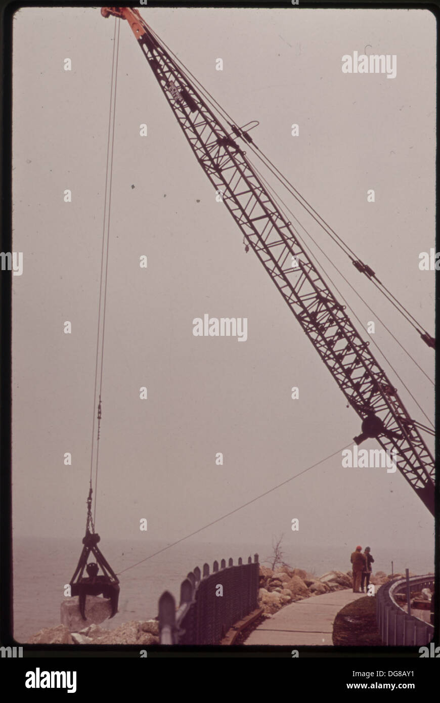 This image shows a crane lifting boulders to reinforce a damaged ...