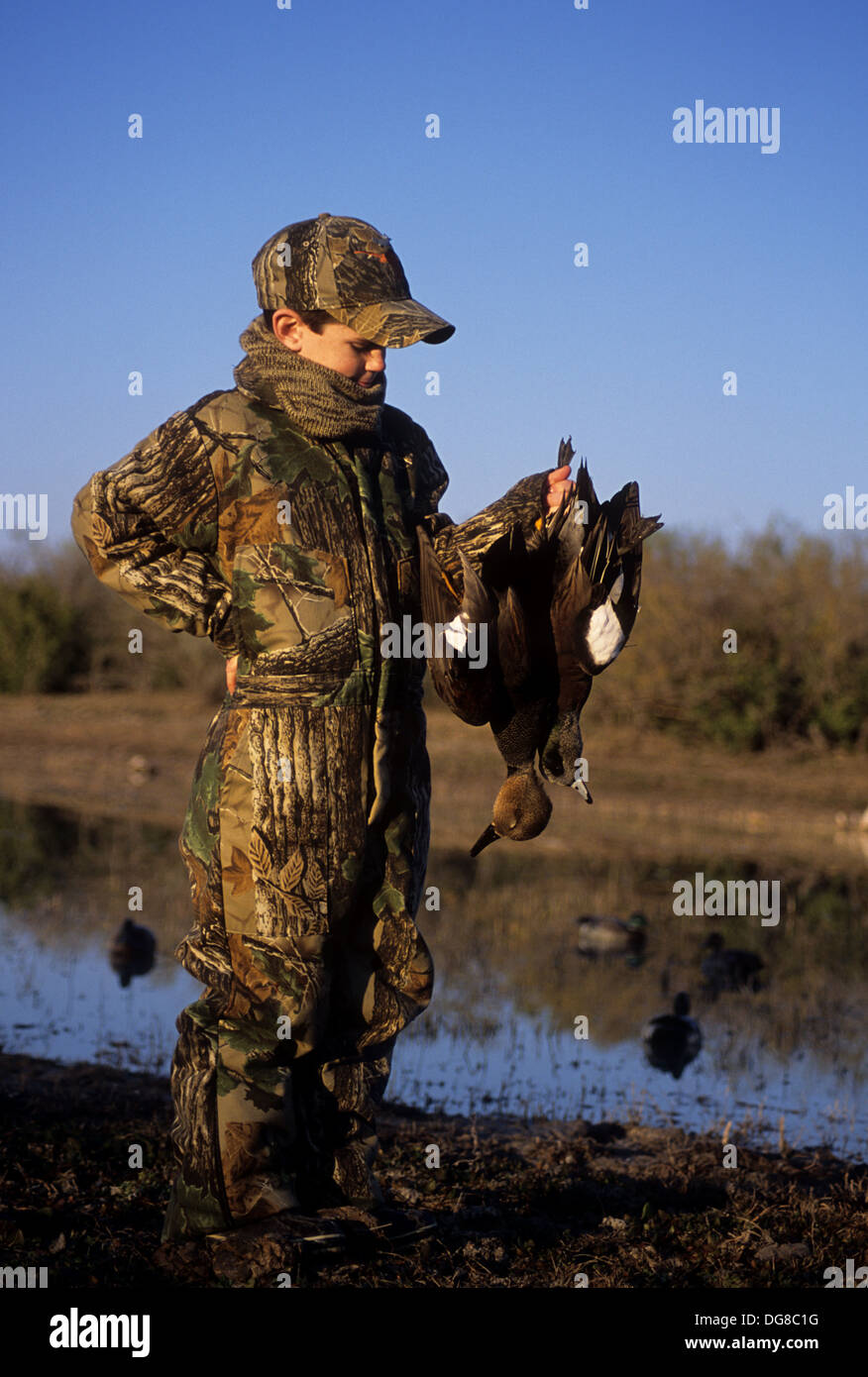 A young boy duck hunter with ducks while hunting on a ranch lake near ...