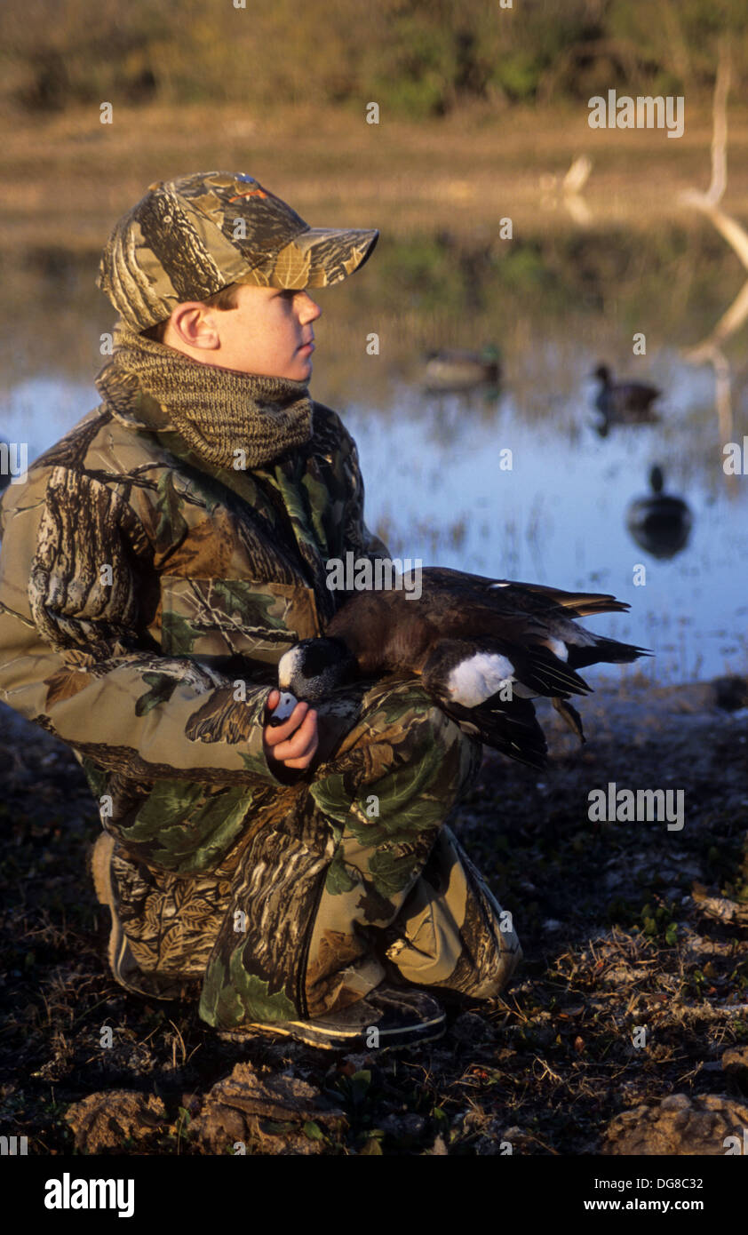A young boy duck hunter with ducks while hunting on a ranch lake near ...