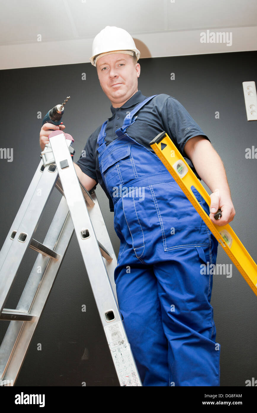 worker with tools, stands on a ladder Stock Photo - Alamy