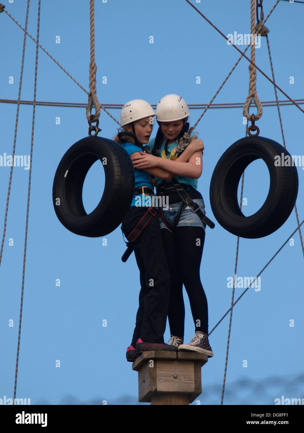 Two teenage girls standing on the top of a post looking scared, part of ...