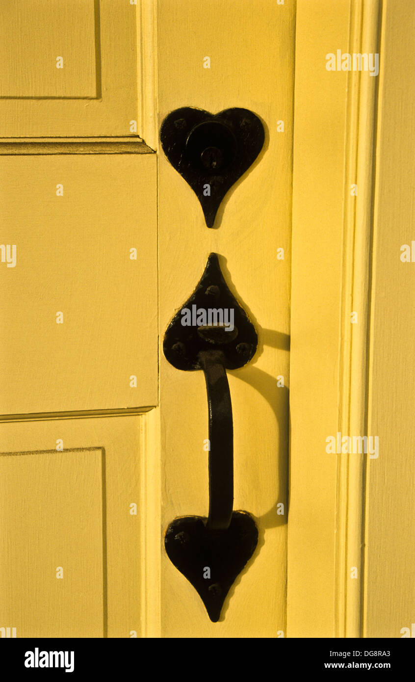 Vintage yellow house front door with heart shaped handle, close up ...